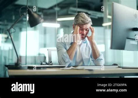 Exhausted Overworked Mature Office Worker Sitting In The Workplace