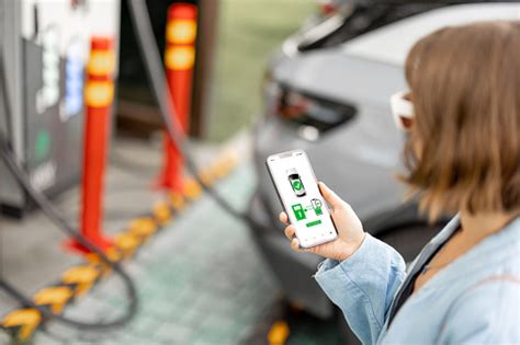 차량 충전을 위한 실행 중인 응용 프로그램이 있는 스마트폰을 들고 Brand Name Smart Phone에 대한 스톡 사진 및 기타 이미지 Brand Name