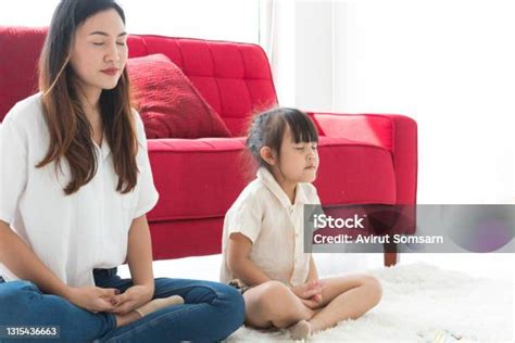 요가 운동을 하는 어린 어머니와 어린 딸이 집에서 바닥에 앉아 있습니다 어머니는 그녀의 여자 딸 연습 가족 명상을 가르칩니다