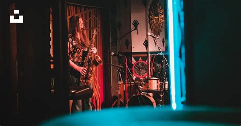 벽시계 근처 무대에서 색소폰을 연주하는 여자 사진 Unsplash의 무료 싱가포르 이미지