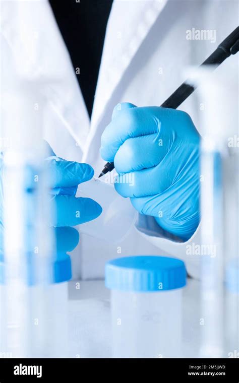 Left Handed Female Scientist Labeling Samples With Blue Gloves And