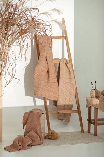 나무 벤치에 흙 색조의 천연 와플 린넨 수건과 대나무 칫솔 등나무 바구니 및 비누 디스펜서가있는 수건 사다리 데일리 바디 케어