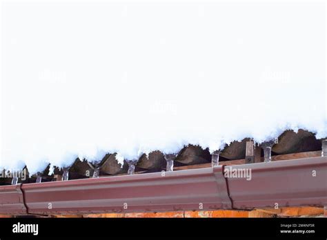 Snow Drifts On The Roof And Icicles Hanging Over The Gutter Stock Photo Alamy