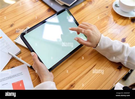 Close Up Image Of A Female Hands Is Tapping On Tablet Touchscreen Computer On Wooden Working