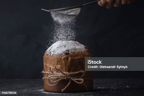 전통적인 이탈리아 크리스마스 케이크 Panettone은 검은 배경에 황마 실로 묶여 있습니다 생과자 요리사는 건포도와 함께 과일 부활절 케이크에 체를 통해 가루 설탕을