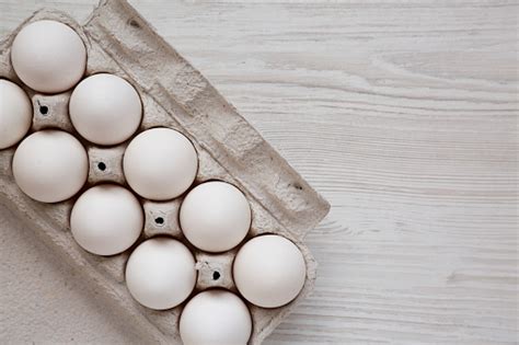 흰색 나무 표면에 종이 상자에 조리되지 않은 유기농 흰 계란 상단 보기 위에서 플랫 평지 오버헤드 공간을 복사합니다 농장에 대한