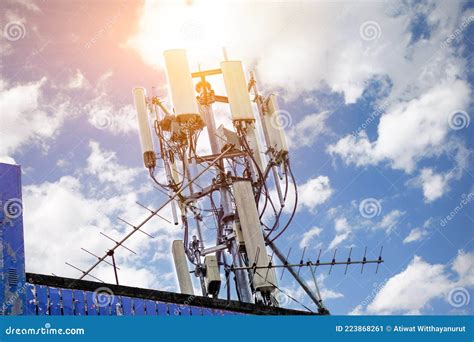 Communication Tower With Antennas On The Top Of Building And Bright Blue Sky With Sun Flare And