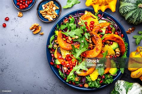 구운 호박 조각 붉은 양배추 아보카도 양상추 루꼴라 석류 및 견과류를 곁들인 건강한 샐러드 비건 채식 식사 편안한 음식 회색 테이블 배경입니다 평면도 가을에 대한 스톡 사진