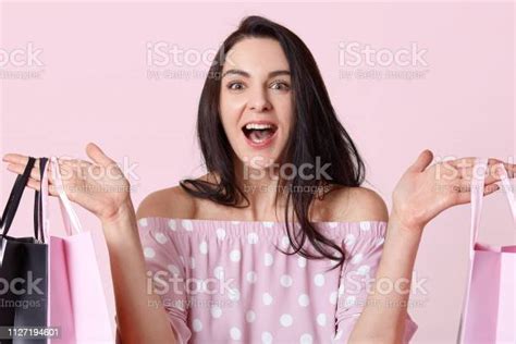 얼굴만 기쁘게 어두운 머리 젊은 여자의 쇼핑 가방을 보유 하 고 즐겁게 좋은 기 뻐 날 성공적인 구매 라이트 핑크 배경 위에 모델은 사람과 구매 개념 가방에 대한 스톡 사진