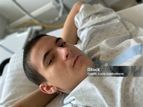 병원 병동에 있는 환자가 수술을 받을 준비를 했습니다 그는 병원 가운을 입고 있으며 주변에 의료 장비가 있습니다 그는 의료진이 그를 수술실로 데려올 것으로 기대하는 방을