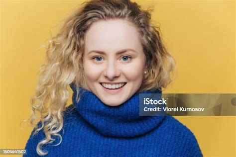 밝은 머리 파란 스웨터를 입은 기쁜 여자 활짝 웃는 얼굴 하얀 이빨 성공적인 하루를 보낸 후 만족합니다 노란색 배경 25 29