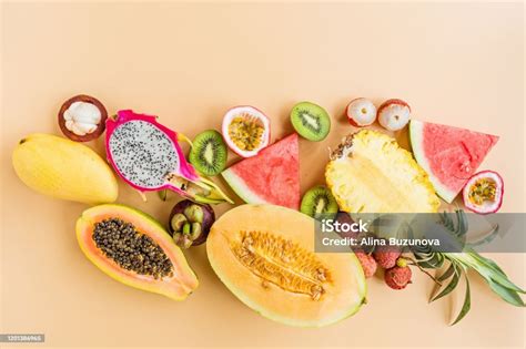 파스텔 오렌지 배경에 신선한 이국적인 과일과 열대 야자수 잎 파파야 망고 파인애플 열정 과일 용 과일 포도 가이 키위 멜론 모형