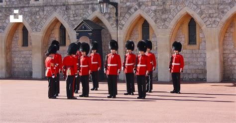 낮에 갈색 콘크리트 건물 앞에 서 있는 빨간색과 검은색 제복을 입은 사람들 사진 Unsplash의 무료 사람의 이미지