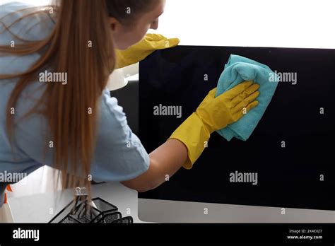 Female Worker Of Cleaning Service Wiping Computer Screen In Office