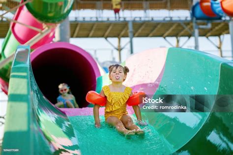 아쿠아 파크에서 워터 슬라이드를 타고 있는 어린 미취학 소녀 열대 휴양지에서 가족 여름 방학을 즐기며 즐거운 시간을 보내는 행복한 아이 어린 아이와 아기를 위한 젖은
