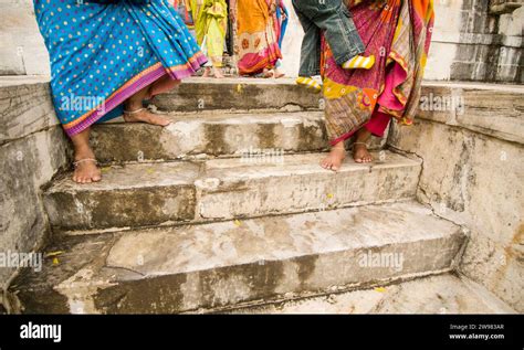Women With Saris And Ankle Bracelets Walk Barefoot On Well Worn Marble