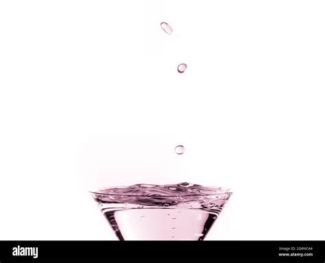 Close Up Of Pink Cocktail Drops Falling Into A Glass On White
