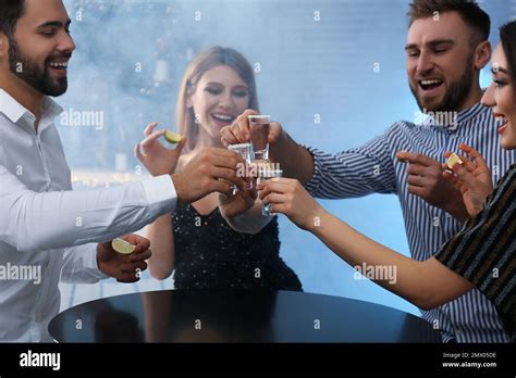 Young People Toasting With Mexican Tequila Shots At Table In Bar Stock