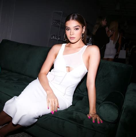 A Woman Sitting On Top Of A Green Couch In A White Dress And Pink Nail Polish