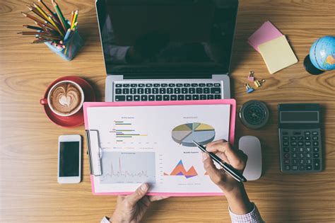 사업가는 테이블에 금융 차트와 노트북과 손을 보고서 논문 및 사무실 테이블 비즈니스 차트 팀워크 컨셉을 갖춘 기업 비즈니스 기획 맨 위 보기입니다 금융에 대한 스톡 사진 및