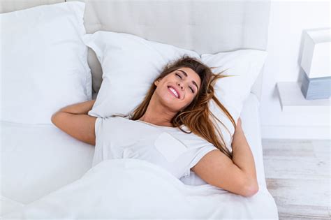 젊은 미소 예쁜 아가씨의 이미지는 실내 침대에 누워있다 눈을 감고 개념을 깨우는 아름다운 여자는 침실에서 그녀의 침대에서 깨어 그녀는 스트레칭과 미소 편안한에 대한 스톡