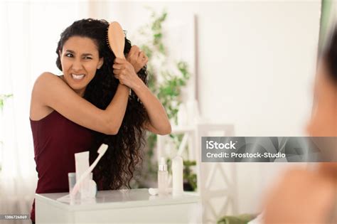 좌절 밀레니엄 여성 데 문제 칫 솔질 그녀의 얽힌 머리 근처 거울 에 화장실 빈 공간 볼륨감 있는 머리에 대한 스톡 사진 및