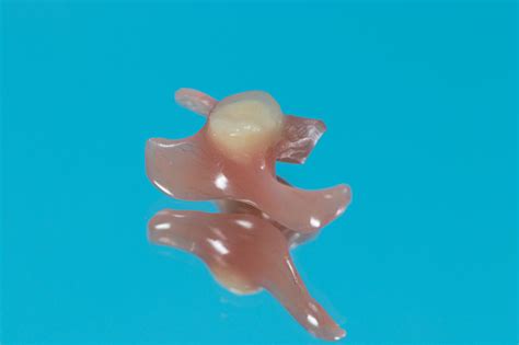 Artificial Tooth Prosthesis In On A Blue Background Single Removable