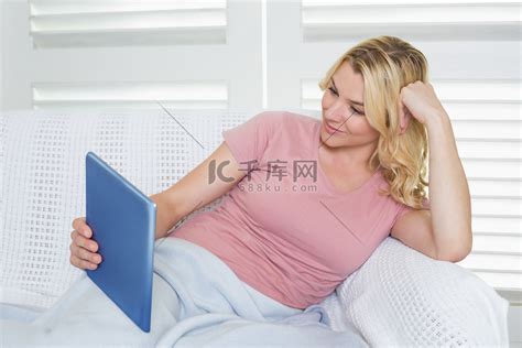 快乐的金发女郎在沙发上用她的平板电脑放松高清摄影大图 千库网