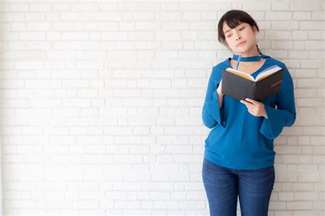 집에서 콘크리트 시멘트 흰색 배경에 스탠딩 생각하고 쓰기 노트북을 웃고 아름다운 아시아 여성 책 교육 및 라이프 스타일 개념에 소녀 숙제 가정 생활에 대한 스톡 사진 및