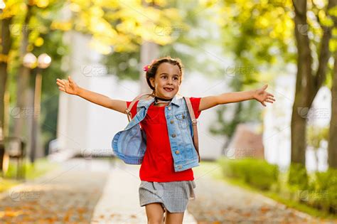 这个小女生背着书包，笑着跑着。学校、学习、教育、友谊、童年的概念。