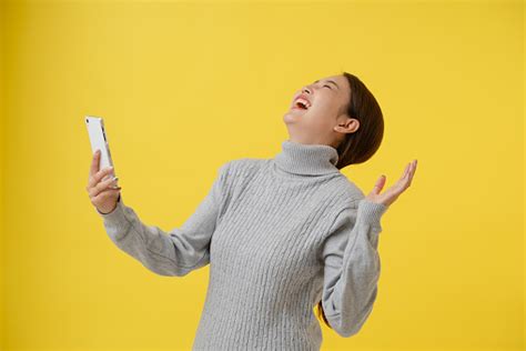 여성 아시아 관광객의 초상화 모바일 응용 프로그램 회색 셔츠 매우 재미있는 감정 노란색 배경에 고립 된 프리젠 테이션을위한 빈 템플릿 휴대 전화를 들고 30 34세에 대한