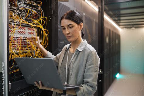 Waist Up Portrait Of Female Network Engineer Connecting Cables In Server Cabinet While Working