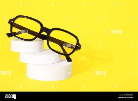 Podium with stylish sunglasses on yellow background Stock Photo - Alamy