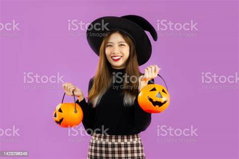 할로윈 테마 검은 색 의상을 입은 젊은 아시아 여성이 마녀 모자를 쓰고 웃고 보라색 등불에 호박 등불을 들고 있습니다 10월에 대한 스톡 사진 및 기타 이미지 Istock