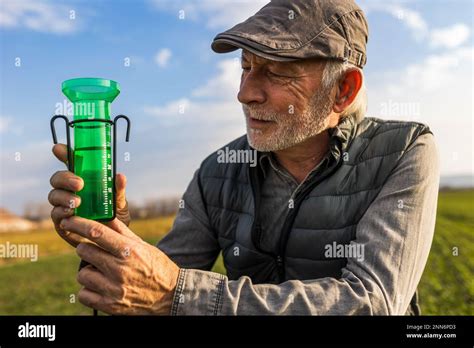 Senior Farmer Looking At Water Gauge For Rain Measuring In Field Or Garden Stock Photo Alamy