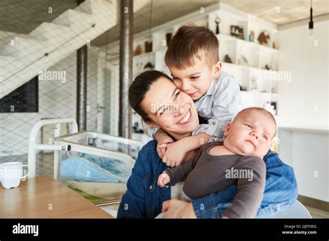 Happy Single Mother With Baby And Big Brother At Home In The Living Room Stock Photo Alamy