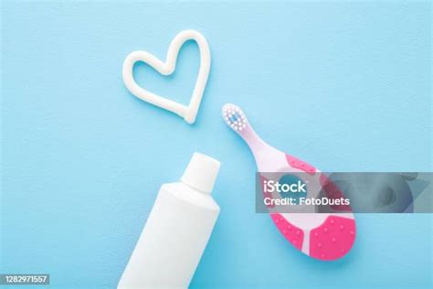 흰색 심장 모양 치약 튜브 밝은 파란색 테이블 배경에 분홍색 칫솔 파스텔 색상 아기 치아 위생 근접 촬영 하향 보기 0명에 대한