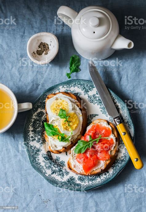 맛 있는 건강 한 아침 식사 또는 간식크림 치즈와 함께 샌드위치 삶은 계란과 훈제 연어와 그린 차 파란색 배경에 평면도 건강한