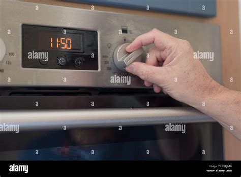 Man Setting The Timer Clock On The Oven Turning Knob To Set The Timer Cost Of Living And