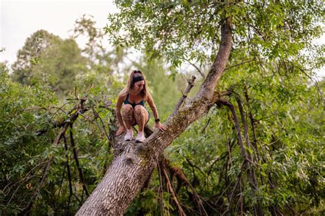 An Active Woman Exercises In A Park Using A Tree For Strength And