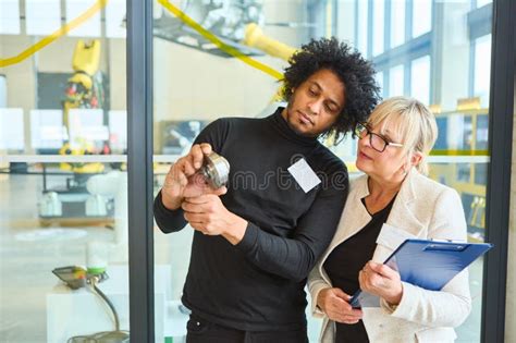 Engineers Inspecting Robotic Gripper Part In Industrial Workspace For