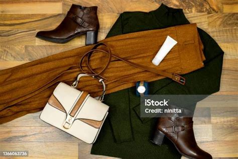 세련된 옷과 액세서리 세트 녹색 스웨터와 골판지 스커트 핸드백 발목 부츠와 갈색 가죽 벨트와 나무 테이블에 튜브 얼굴 크림 플랫 누워 트렌드에 있어야 합니다 0명에 대한