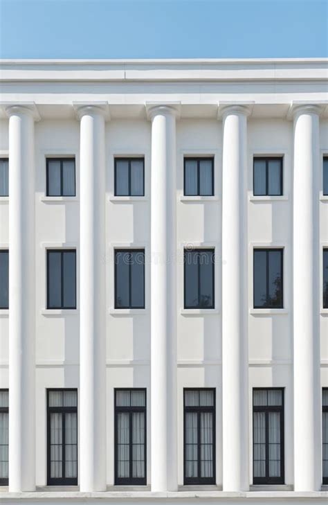 Modern New Classicism Building Facade With White Columns Black Framed Windows Under Clear Blue