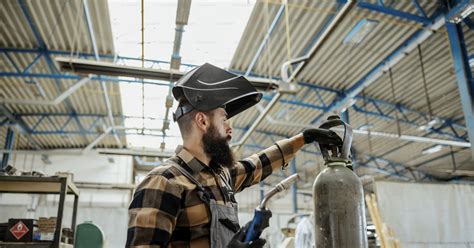 머리에 보호 마스크를 쓴 작업자가 가스 병의 밸브를 풀고 용접을 준비합니다 작업장에서 용접하는 작업자 사진 Unsplash의 초상 이미지