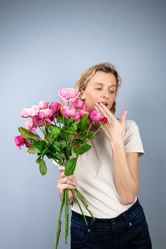 회색 배경 분홍색 모란 장미의 큰 꽃다발을 가진 젊은 금발 소녀 3 월 8 일 첫 데이트 얼굴에 감정 웃는 소녀 놀란 소녀 손으로 입을 가리고 있습니다