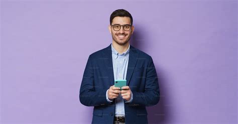 행복한 얼굴로 카메라를 보고 핸드폰을 손에 들고 동료와 파트너와 소통하고 웃고 보라색 배경에 고립된 사업가 사진 Unsplash의 휴대폰 이미지