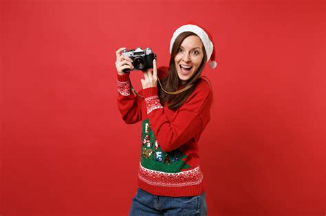니트 스웨터와 빨간 배경에 고립 된 복고풍 빈티지 사진 카메라 들고 크리스마스 모자에 밝은 젊은 산타 소녀 행복 한 새 해 2019 축 하 휴일 파티 개념입니다 복사 공간을