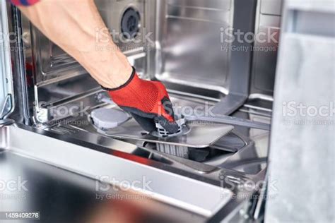 가전 제품의 개념 유지 보수 서비스 작업자가 식기 세척기의 필터를 청소합니다 음식 찌꺼기 필터를 확인하는 남성 수리공 수리에