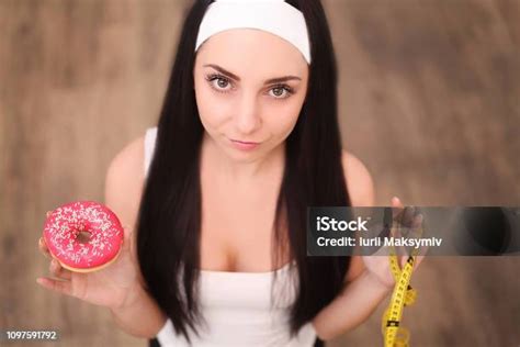 도넛과 측정 테이프를 들고 젊은 여자 여자는 나무 바탕에 서 있다 정상에서 전망입니다 건강 한 식 생활의 개념입니다 다이어트입니다 과체중에 대한 스톡 사진 및 기타 이미지