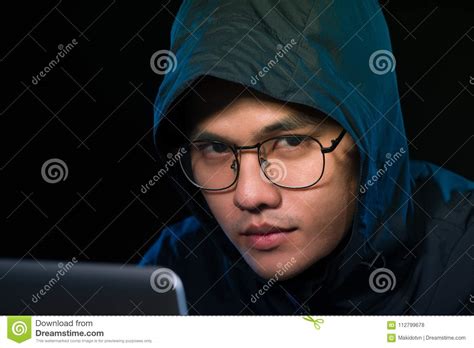 Asian Hacker Hacking Computer Network With Laptop In Dark Cyber
